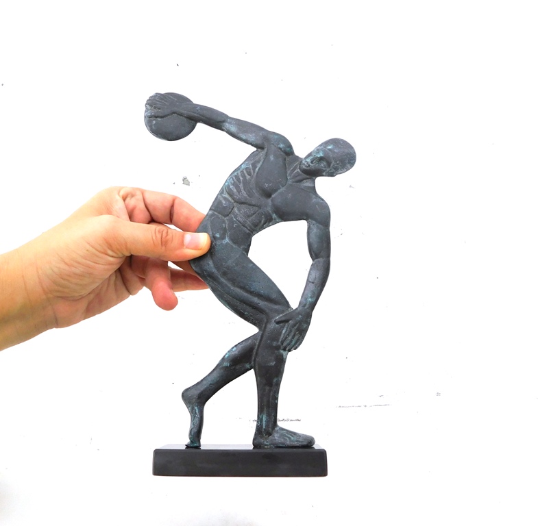 A discus thrower is depicted about to release his throw, bronze sculpture